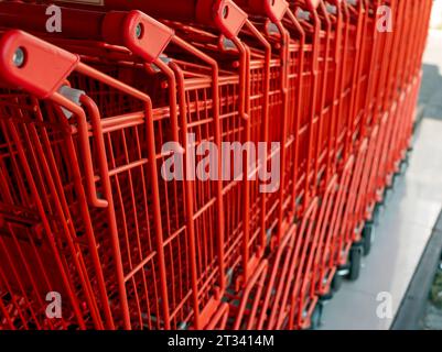 Row of metallic shopping carts with red handles neatly arranged inside ...
