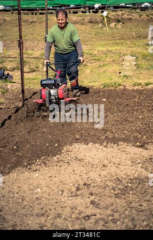 A farmer man plows the land with a cultivator. Machinery cultivator for ...