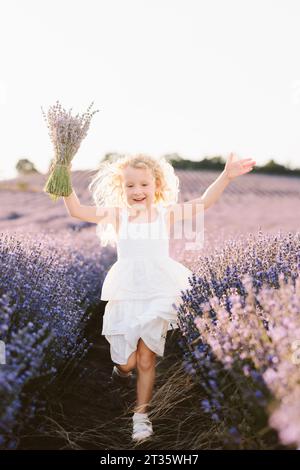 happy girl running in lavender field holding hat in hand, fluttering ...