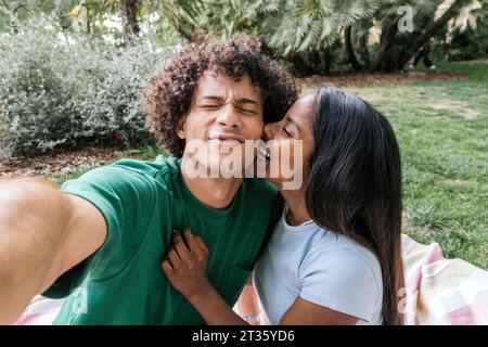 smiling boyfriend hugging girlfriend in sweater with gift at ...