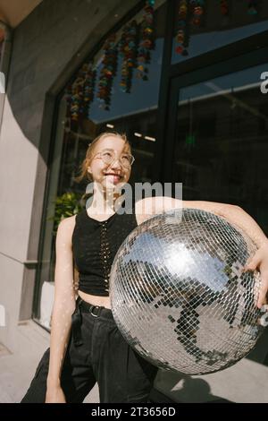 Woman holding disco ball on blue background Stock Photo - Alamy