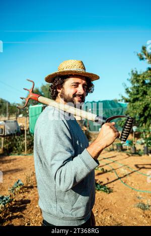Portrait of horticulturist standing on farm plantation with box of red ...