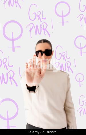 Woman wearing sunglasses showing stop sign in front of wall Stock Photo ...