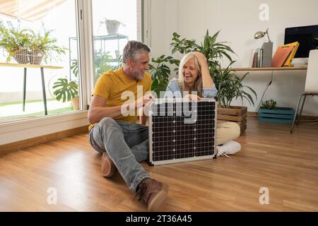 Smiling couple sitting with solar panel on grass in back yard Stock ...