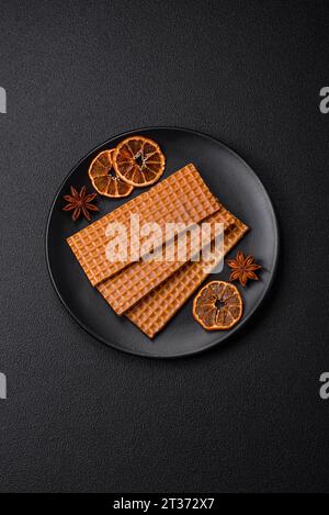 Delicious sweet crispy rectangular waffles on a ceramic plate on a dark ...