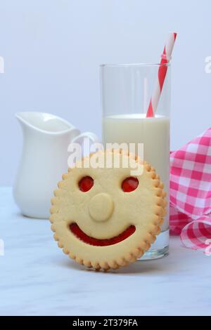 Pastry with smiley face and glass of milk Stock Photo - Alamy