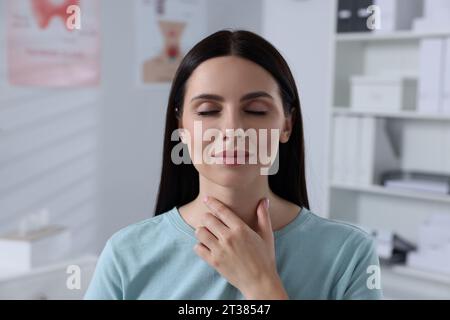 Endocrine system. Young woman doing thyroid self examination on light ...