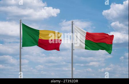 Benin and Madagascar flags waving together on blue cloudy sky, two country relationship concept ...