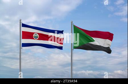 Costa Rico and Sudan flags waving together in the wind on blue cloudy ...