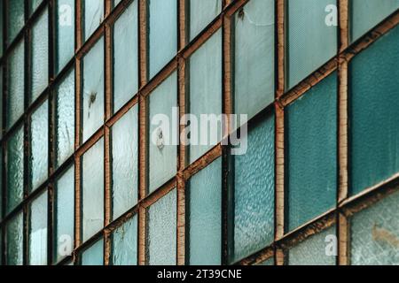 Old grid windows with broken glass on exterior wall of an old abandoned ...
