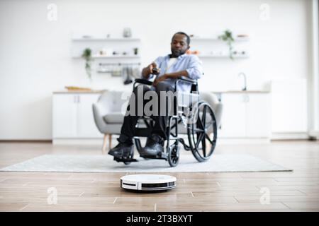 Smart robotic vacuum operated by happy african man with mobility ...