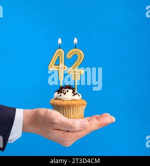 Birthday cupcake with candle number 42 on a red background with blue ...
