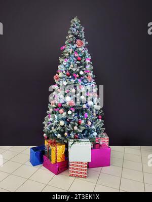Many gift boxes under Christmas tree indoors, closeup. Space for text ...