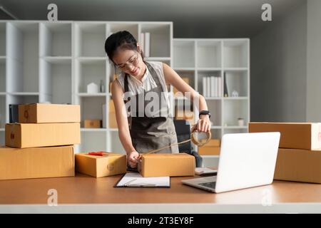 Woman use scotch tape to attach parcel box to prepare goods for the ...