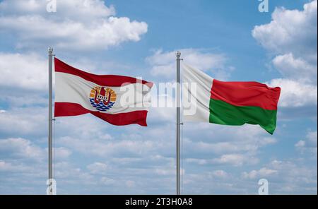 Madagascar and French Polynesia flags waving together on blue cloudy sky, two country ...
