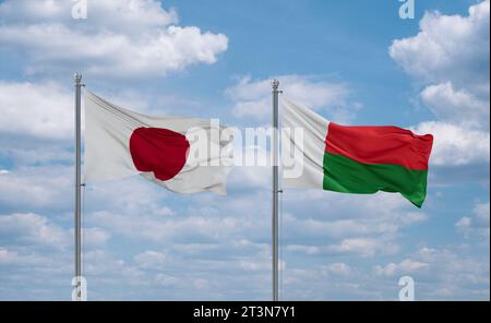 Japan and Madagascar flags waving together on blue cloudy sky, two ...