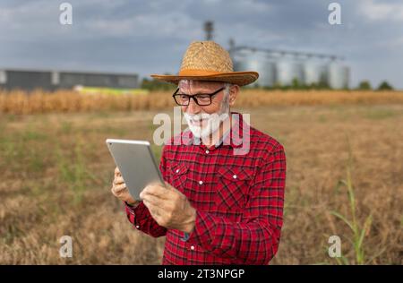 Excited man farmer looking at tablet and celebrating success in field ...