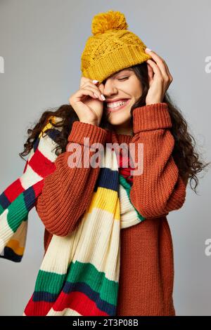 Female model wearing a bobble hat and holding a pair of skis looking ...