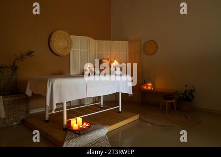 Interior of dark spa salon with couch, shelving units and burning ...