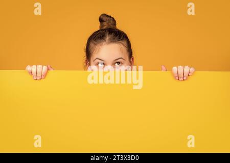 girl hiding behind yellow paper with copy space for advertisement Stock ...