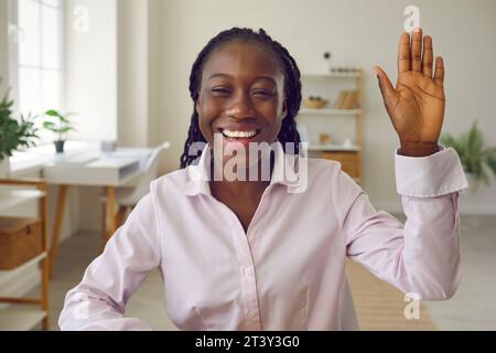 Woman having video call and waving, enjoying coffee in modern home ...