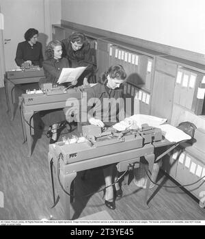 In the 1950s. A female clerk at punch card reader machine overlooking ...