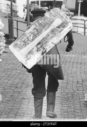 1930s ICE DELIVERY MAN CARRYING LARGE BLOCK OF ICE ON SHOULDER LOOKING ...