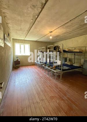 Sleeping quarters with rows of metal bunk beds and various uniform ...