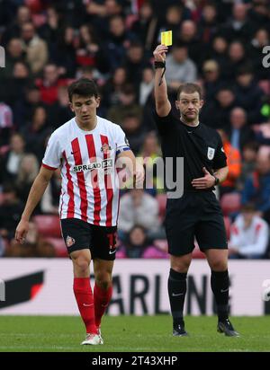 Referee Anthony Backhouse shows a yellow card to Wigan Athletic's ...