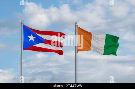 Puerto Rico and Ivory Coast flags waving together in the wind on blue ...