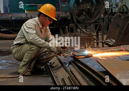 TANGSHAN - JUNE 20: Workers cutting steel ingot behind the continuous ...