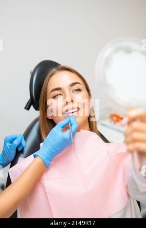 A patient examines his smile in a mirror during a dental checkup ...