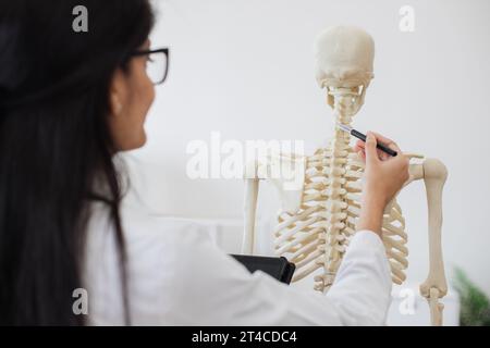 Doctor holding tablet while touching backbone of body model Stock Photo ...
