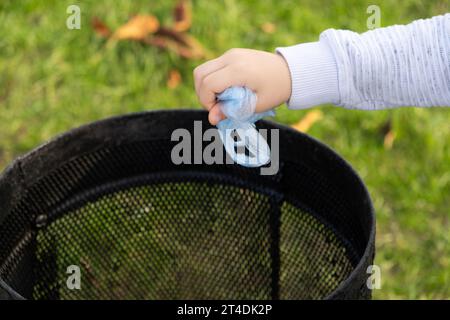 A child throws a plastic bag in the trash. Concept of garbage recycling ...