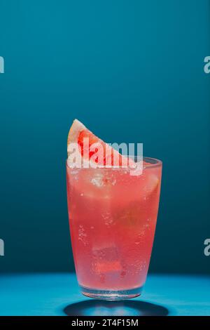 Tasty cocktail with grapefruit, ice cubes and rosemary on white table ...