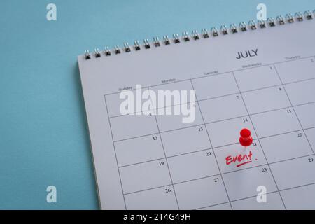 Calendar with word event and red pushpin. On blue desk background, copy ...
