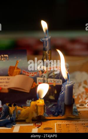 Multi-colored, wax Hanukkah candles burn in a menorah inscribed with ...