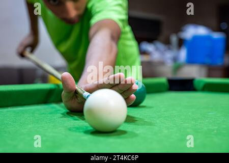 Young adult bearder male playing billiards with his friends focusing on ...