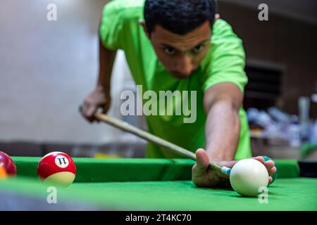 Young adult bearder male playing billiards with his friends focusing on ...