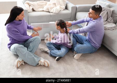 Frozen family warming near radiator at home Stock Photo - Alamy