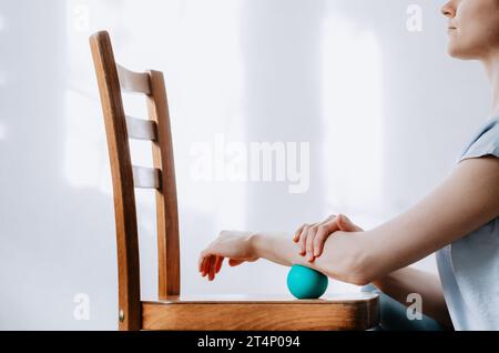 Woman doing forearm massage with therapy ball using chair Stock Photo ...