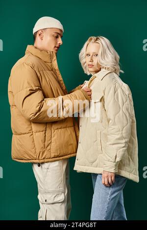 caring man wearing puffer jacket on blonde girlfriend on turquoise ...