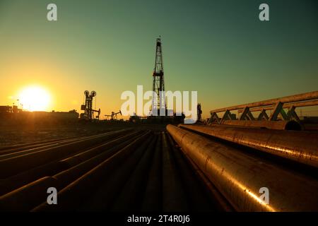 Oil drilling derrick and pipelines in oilfield Stock Photo - Alamy