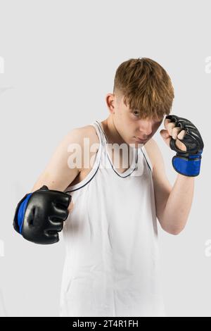 A caucasian teenage boy wearing MMA style boxing gloves celebrating ...