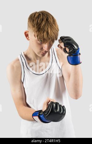A caucasian teenage boy wearing MMA style boxing gloves celebrating ...