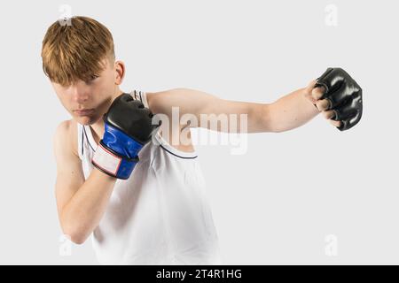 A caucasian teenage boy wearing MMA style boxing gloves celebrating ...