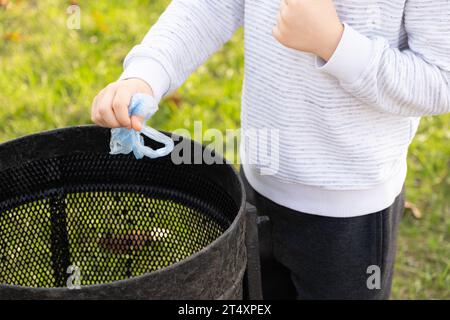 A child throws a plastic bag in the trash. Concept of garbage recycling ...