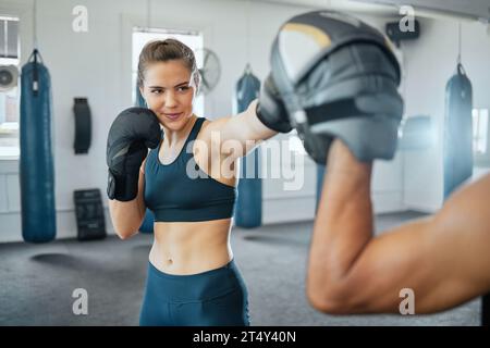 Sporty girl with her trainer are doing self-defence moves in gym Stock ...