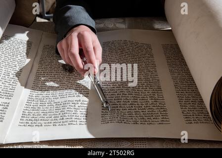 A reader uses a pointer to guide his eyes across the text of a Torah ...