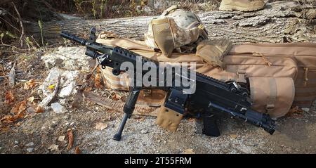 airsoft machine gun black next to a beige bag and helmet Stock Photo ...